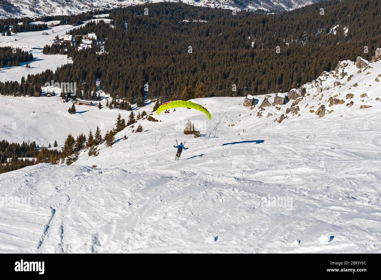 Paraglider taking off from a snow covered slope looking down an alpine ...