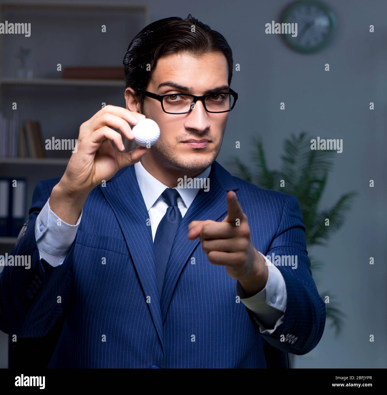 The young employee with golf ball in office Stock Photo - Alamy