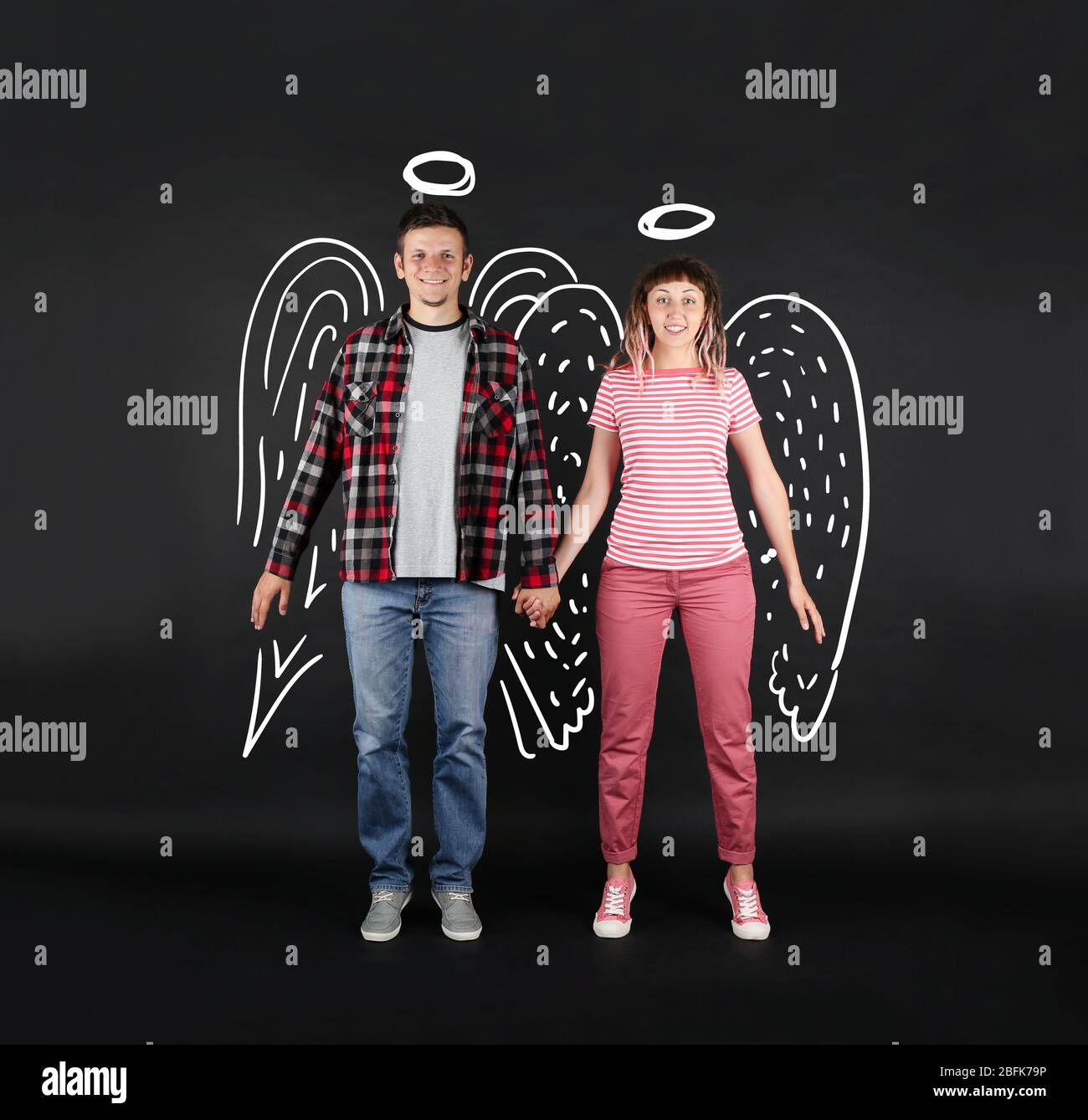 Funny young couple as angels , on black background Stock Photo - Alamy