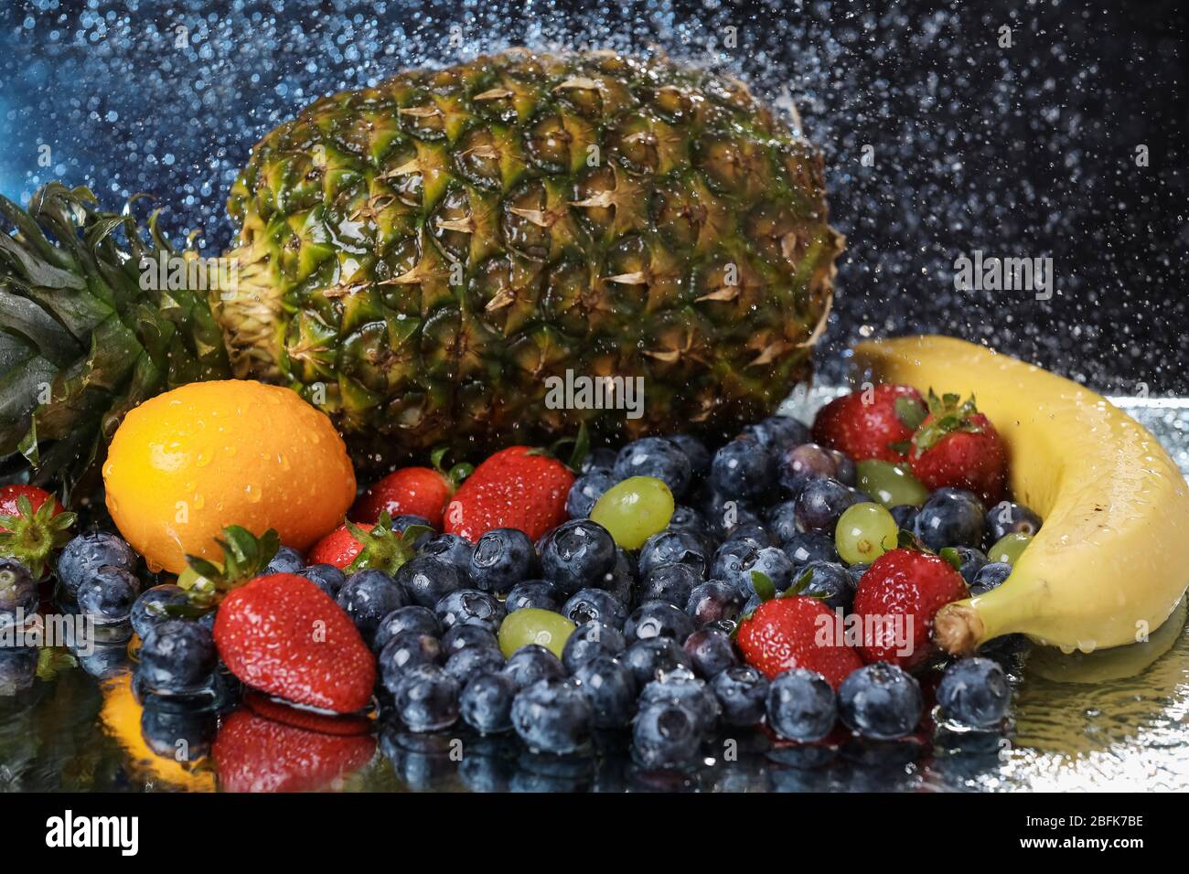 Tropical fruits close up on a table. strawberry, grape, blueberry ...