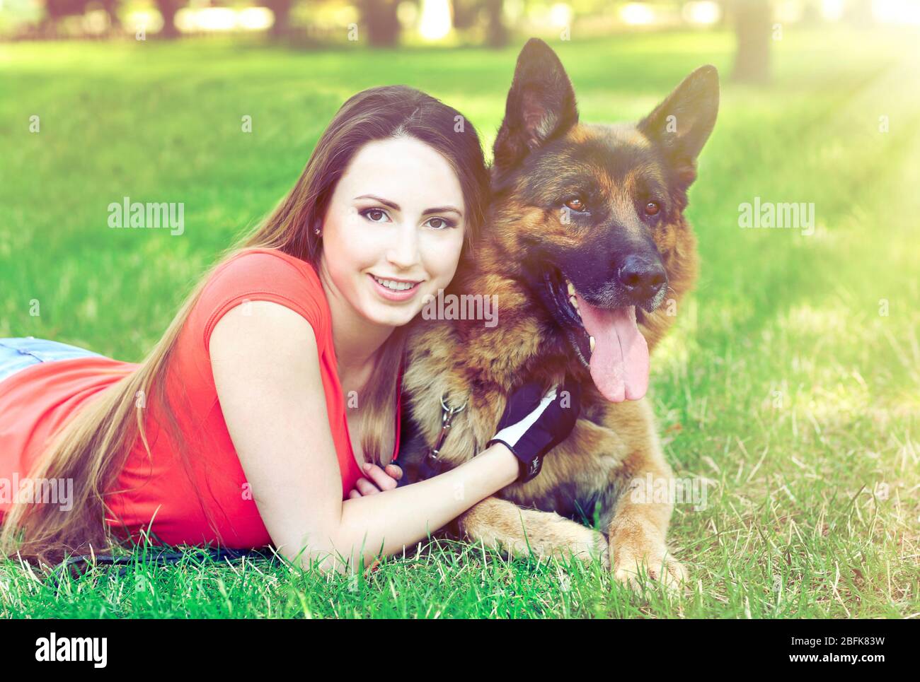Beautiful young girl with dog in park Stock Photo - Alamy