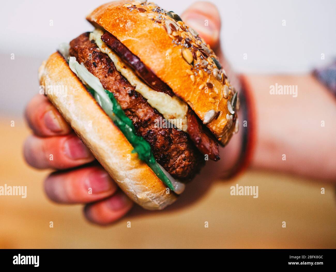 Gourmet Bacon Cheese burger with fresh salad and raw meat. Hands ...