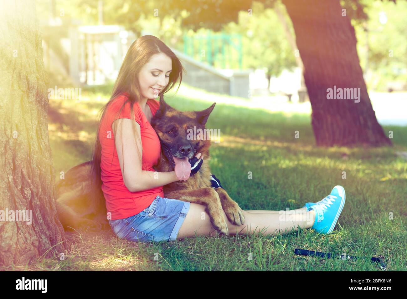 Beautiful young girl with dog in park Stock Photo - Alamy