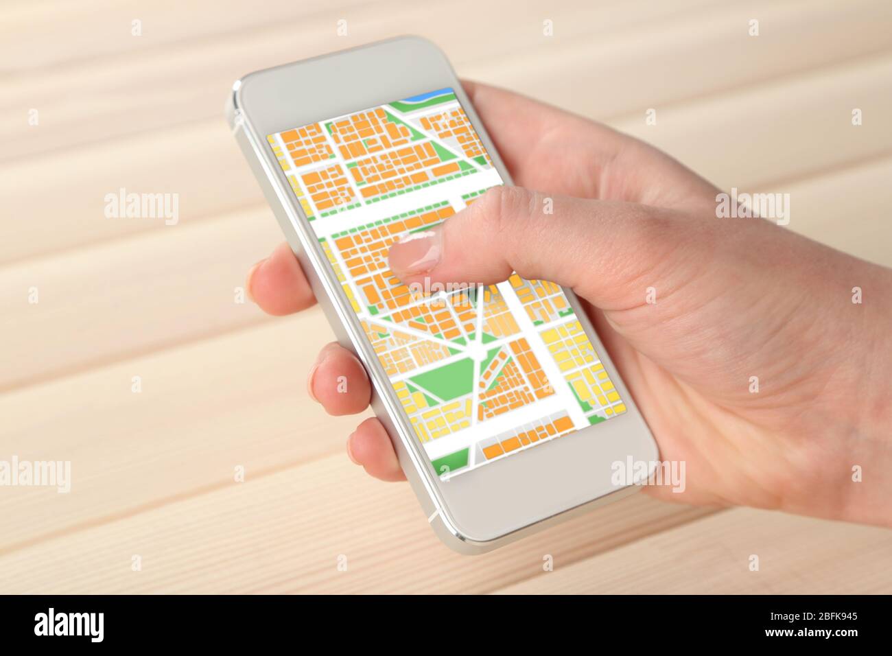 Hand holding smart mobile phone with map gps navigation application on wooden background Stock ...