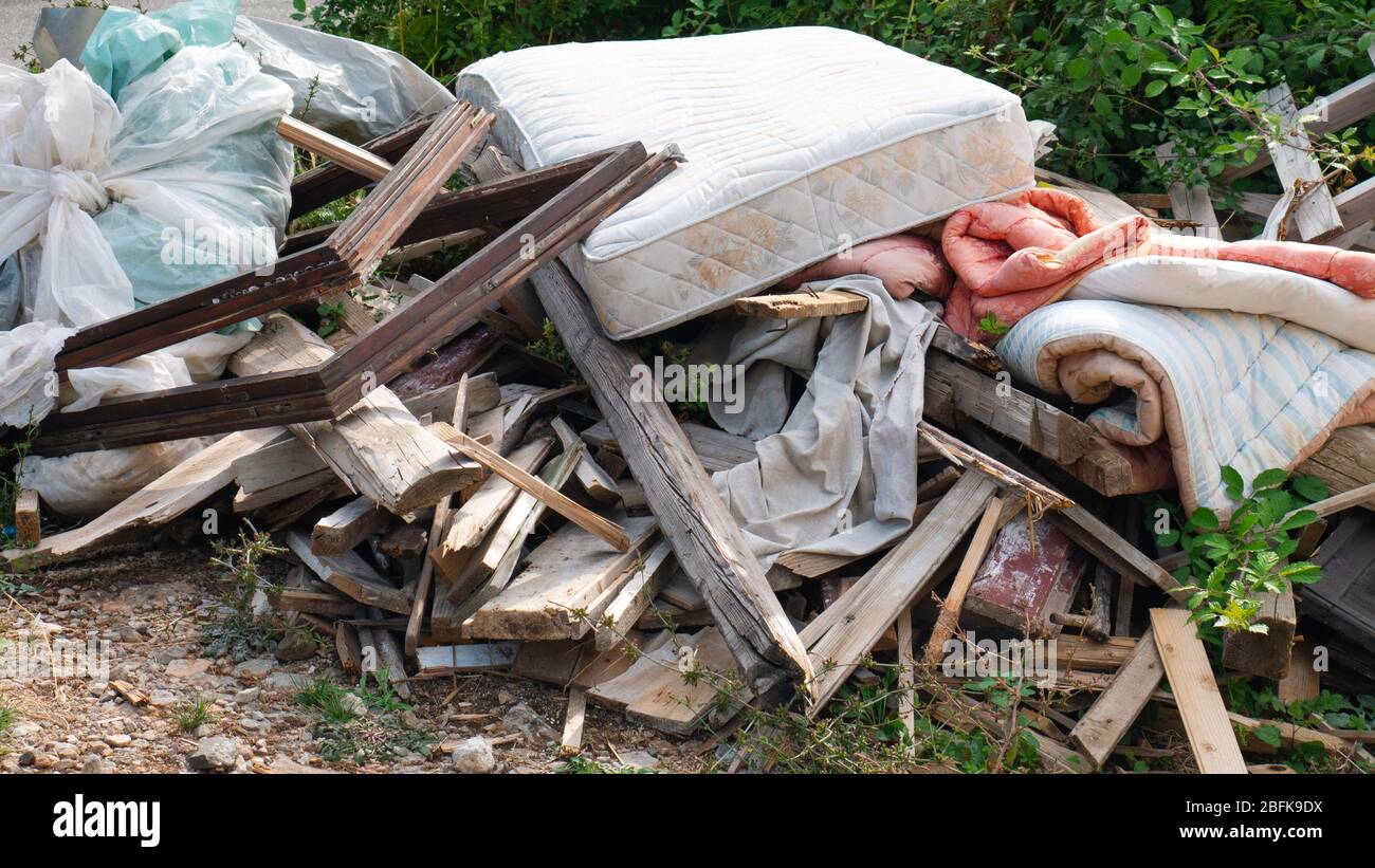 Garbage dumped in the yard near the house: boards, mattress, comforter ...