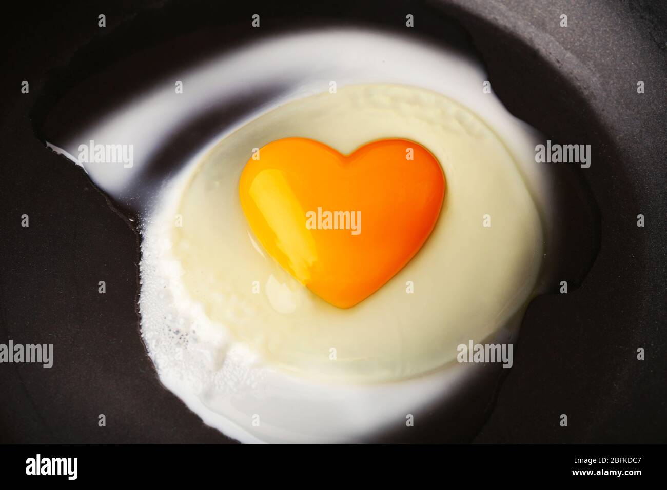Scrambled egg in heart shape on black pan background Stock Photo - Alamy