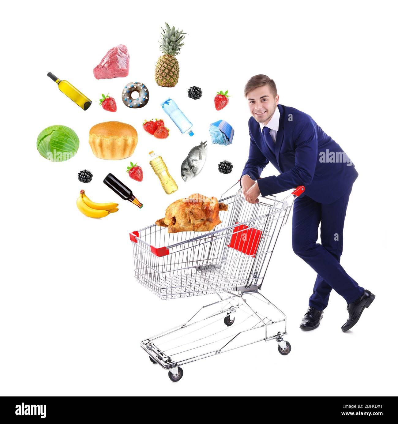 Young man pushing shopping cart with different food, isolated on white ...