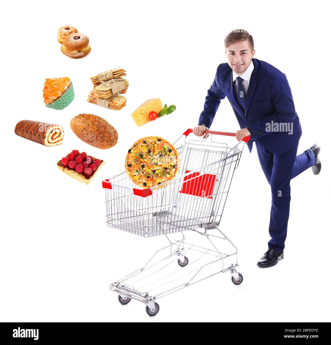 Young man pushing shopping cart with different food, isolated on white ...