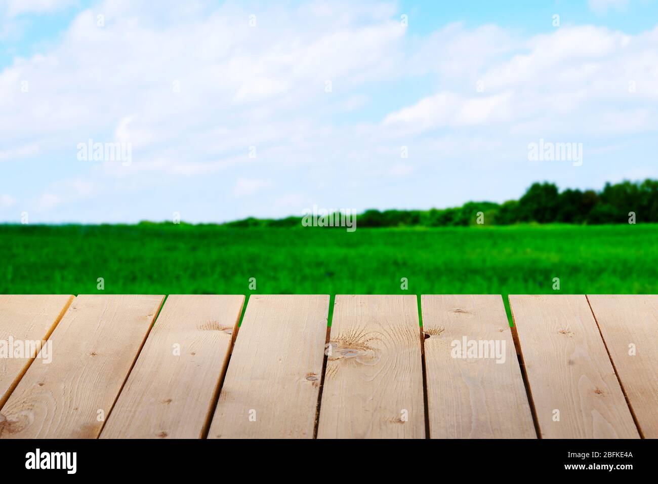 Wooden table with field background Stock Photo - Alamy