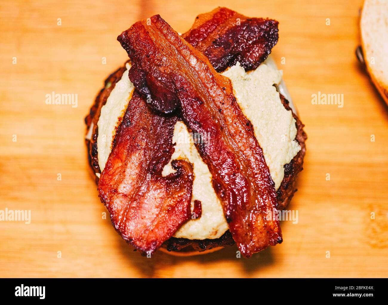 Gourmet Bacon Cheese burger with fresh salad and raw meat. Hands ...