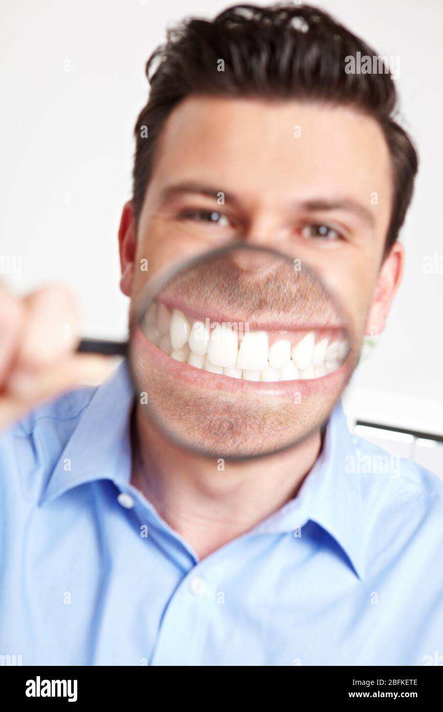 Grinning man in the office with a magnifying glass over his mouth Stock ...