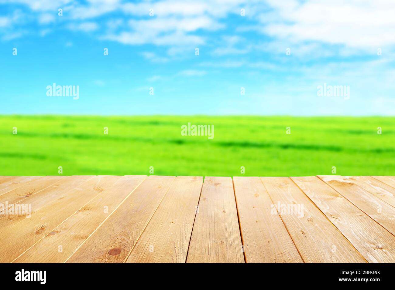 Wooden table with field background Stock Photo - Alamy