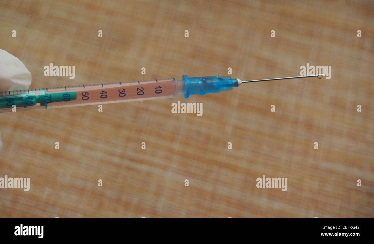 Doctor's hand with a syringe. The syringe is filled with medicine ...