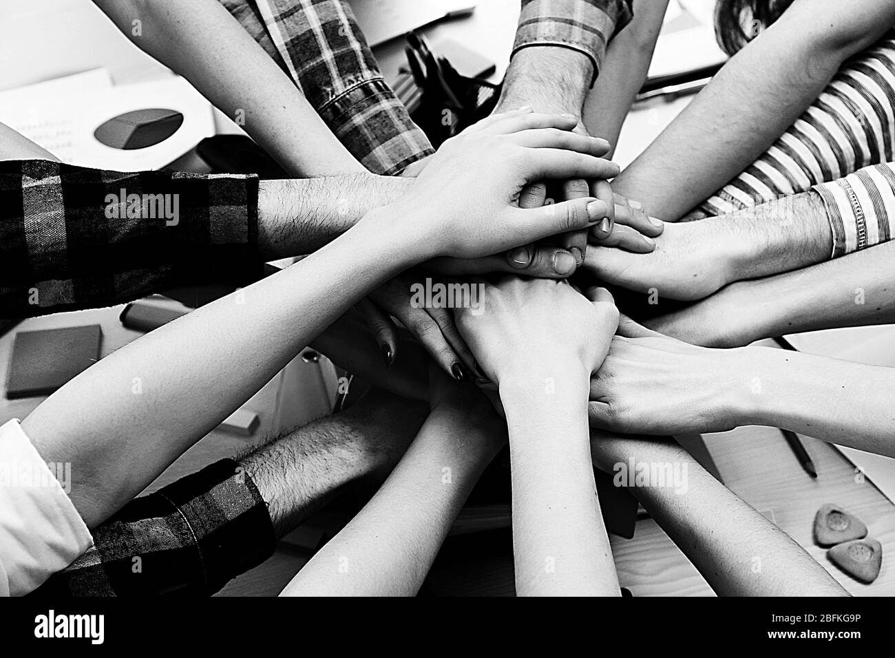 United hands of business team on workspace background top view. Black ...