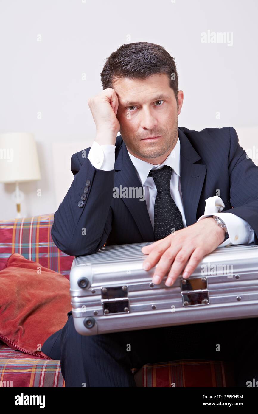 Exhausted manager sits seriously with suitcase in the hotel room Stock ...