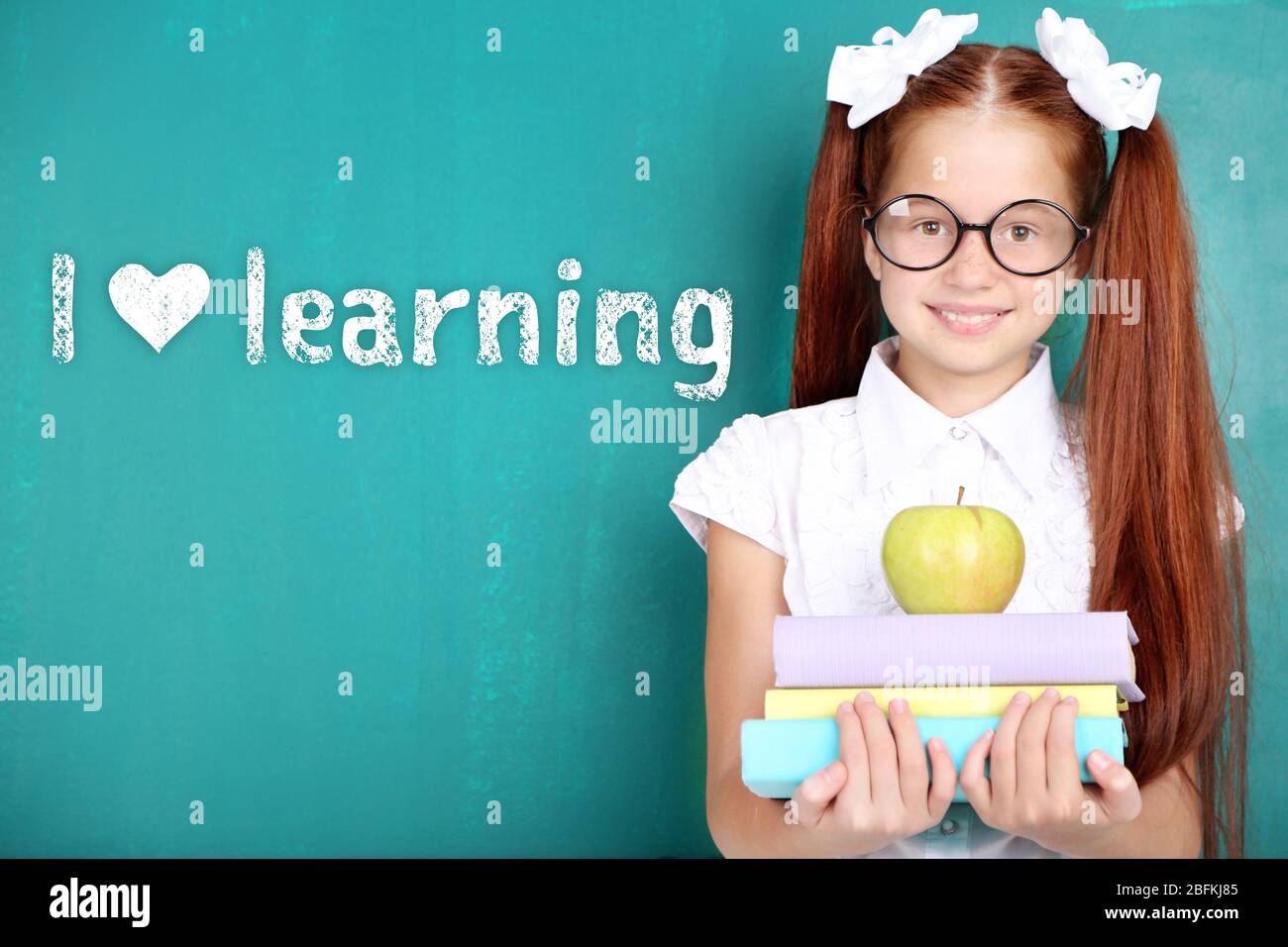 Cheerful girl with books at the blackboard. I love learning concept ...