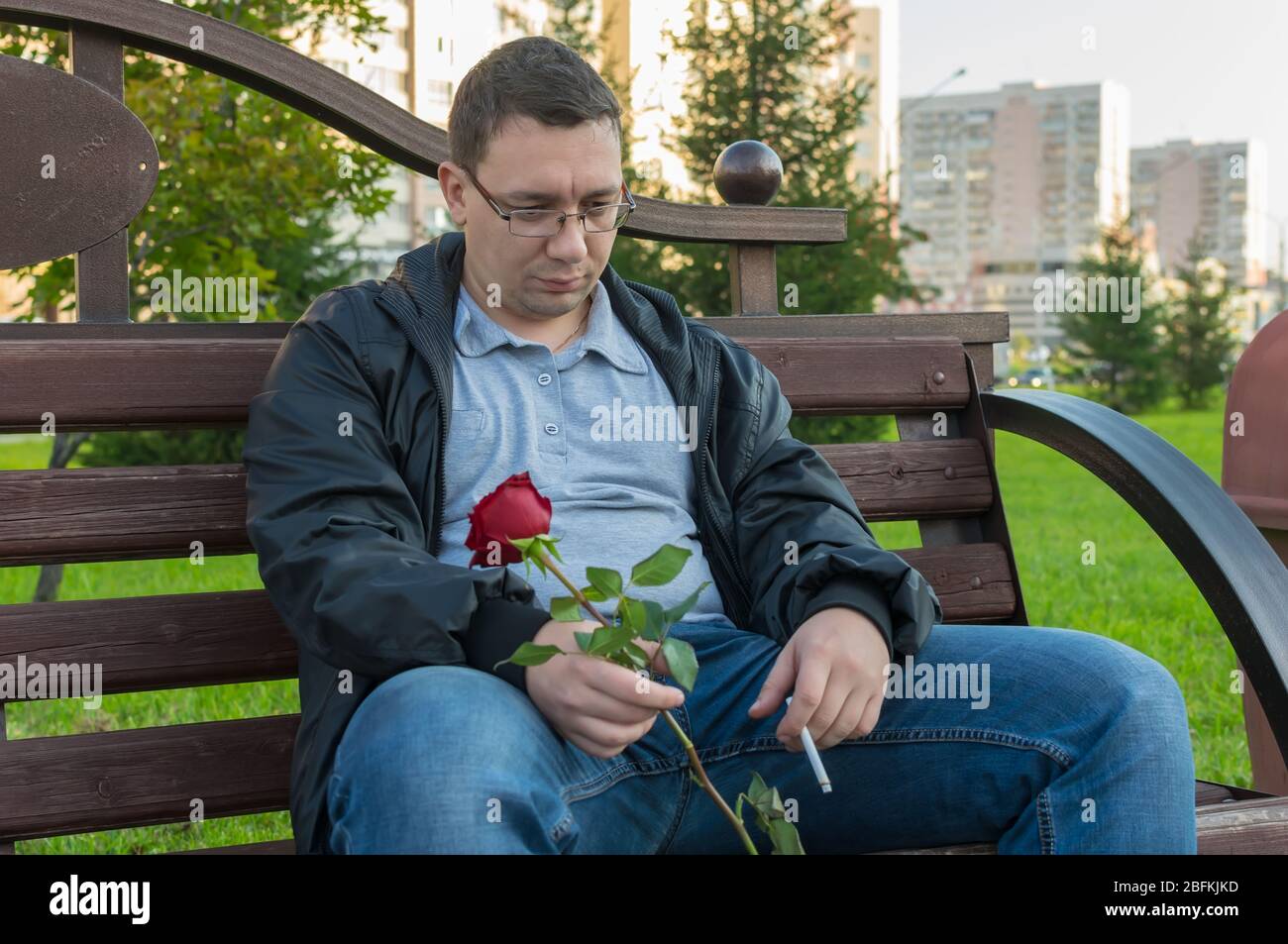a sad, brooding, upset guy with a smoking cigarette and a red rose in ...