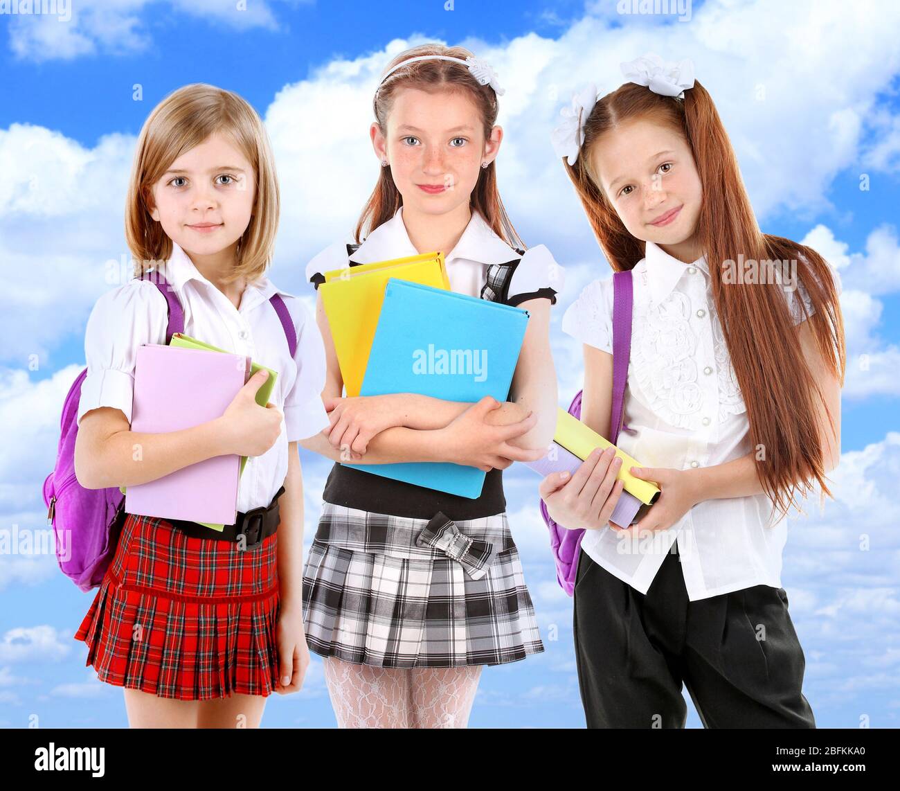 Schoolgirls on blue sky background Stock Photo - Alamy