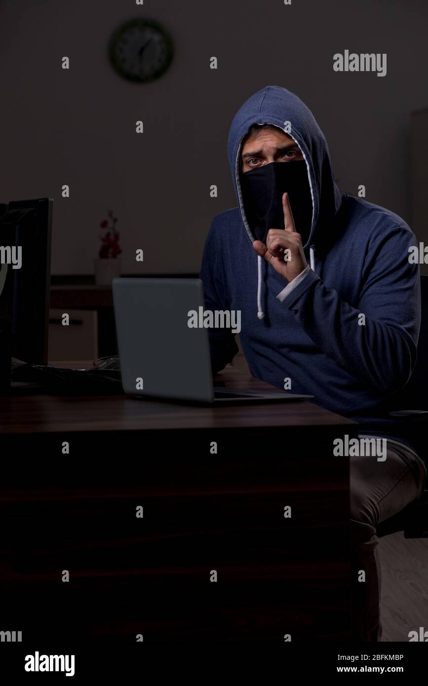 Male hacker hacking security firewall late in the office Stock Photo ...