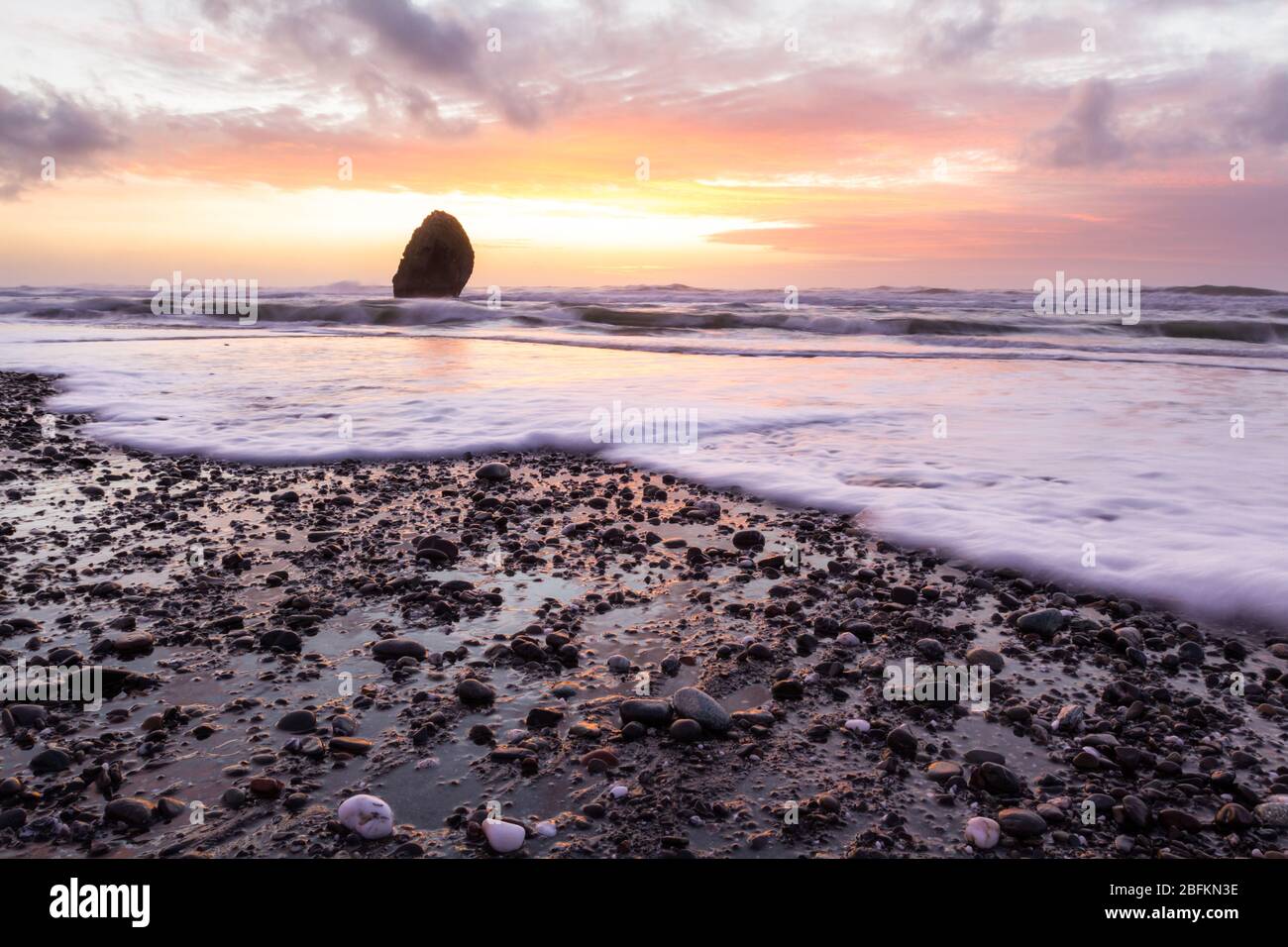 Sunset scene in Gold Beach Oregon with colorful clouds and waves adding ...