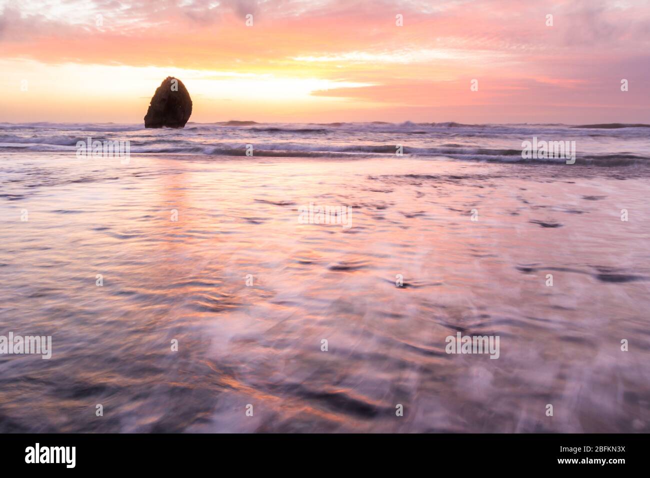 Sunset scene in Gold Beach Oregon with colorful clouds and waves adding ...