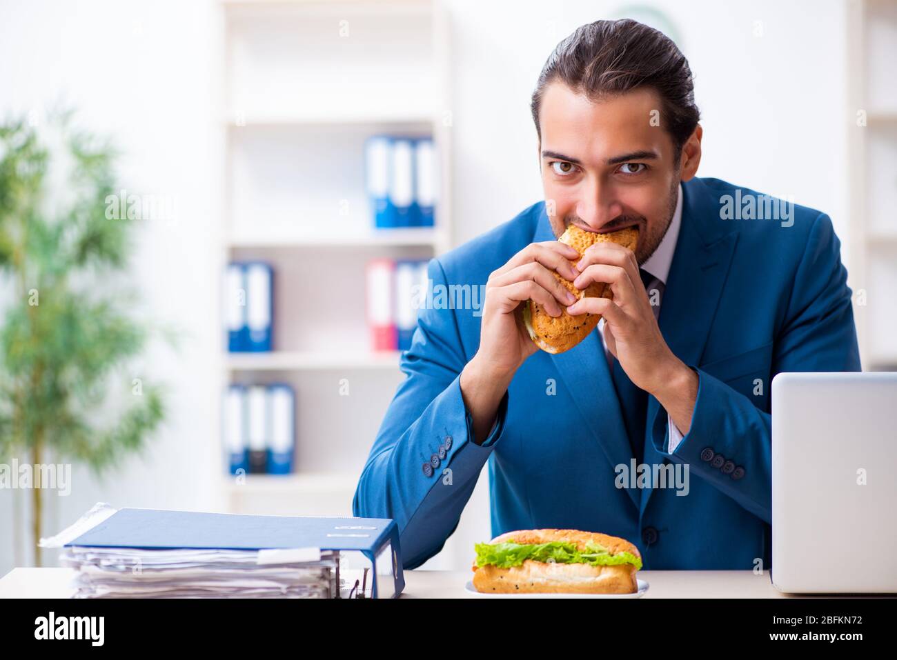 Young employee having breakfast at workplace Stock Photo - Alamy