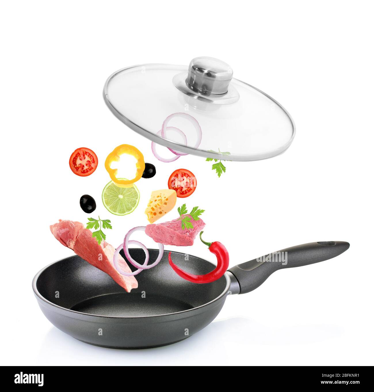 Fresh cut vegetables falling in the frying pan isolated on white Stock ...