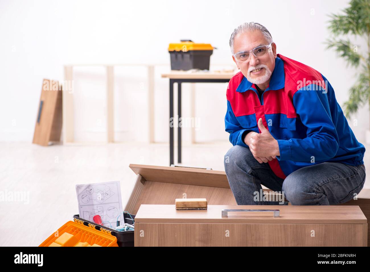 Old carpenter working indoors on furniture Stock Photo - Alamy