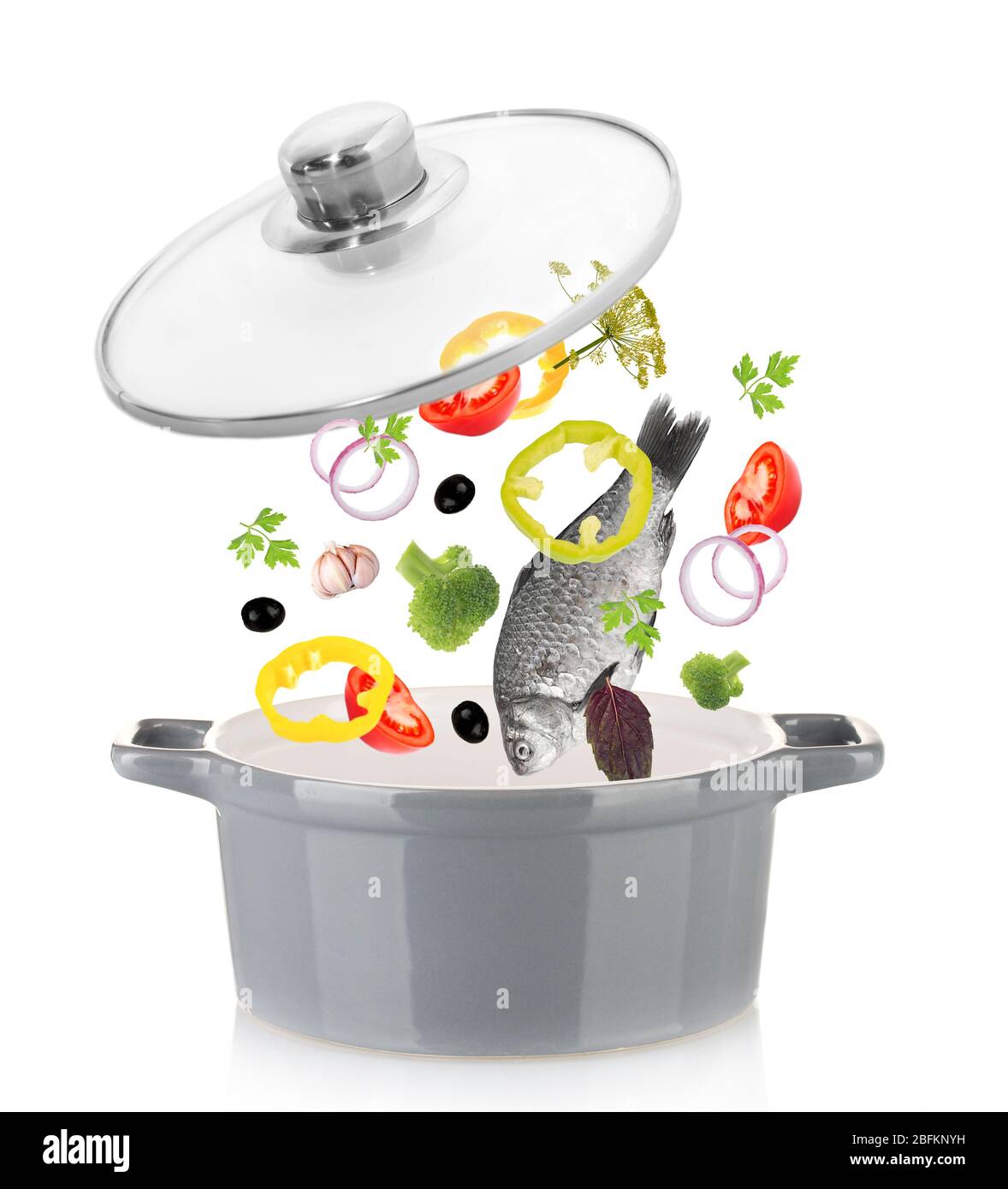 Fresh vegetables falling into a casserole pot isolated on white Stock ...
