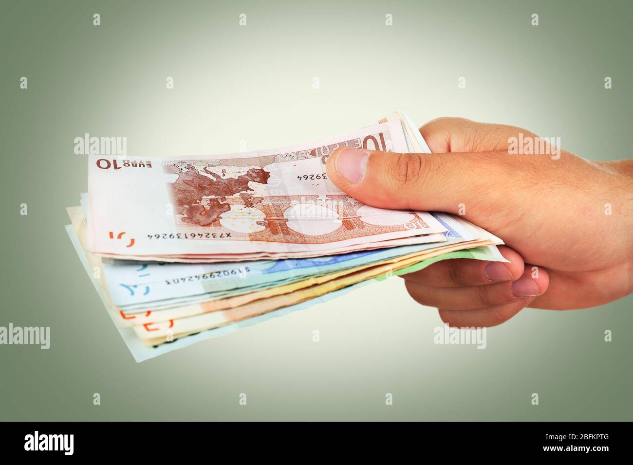 Hand with euro on green background Stock Photo - Alamy
