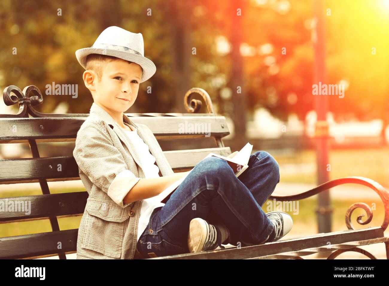 Little boy reading book on bench in the park Stock Photo - Alamy
