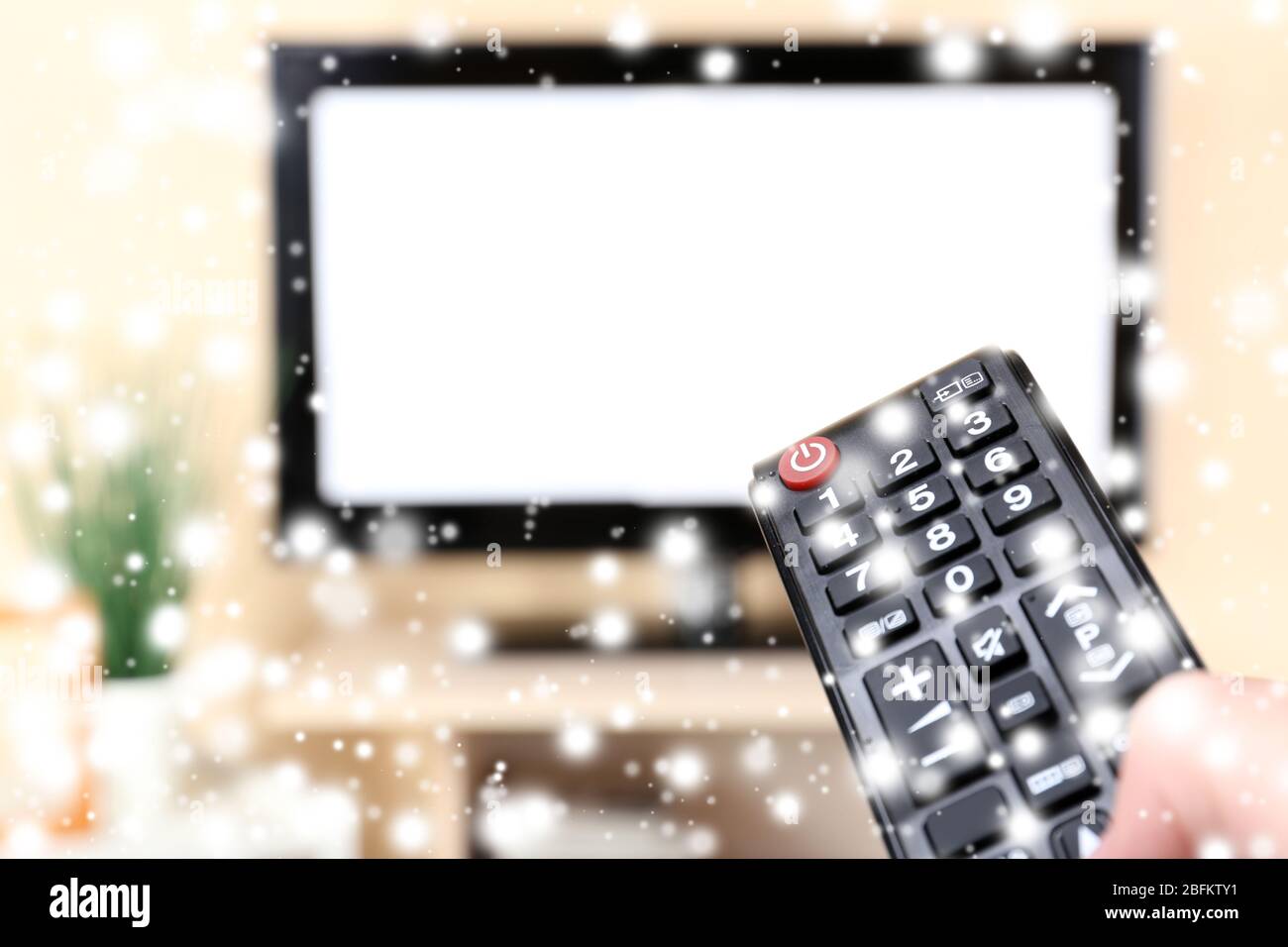 Watching TV and using remote controller over snow effect Stock Photo ...