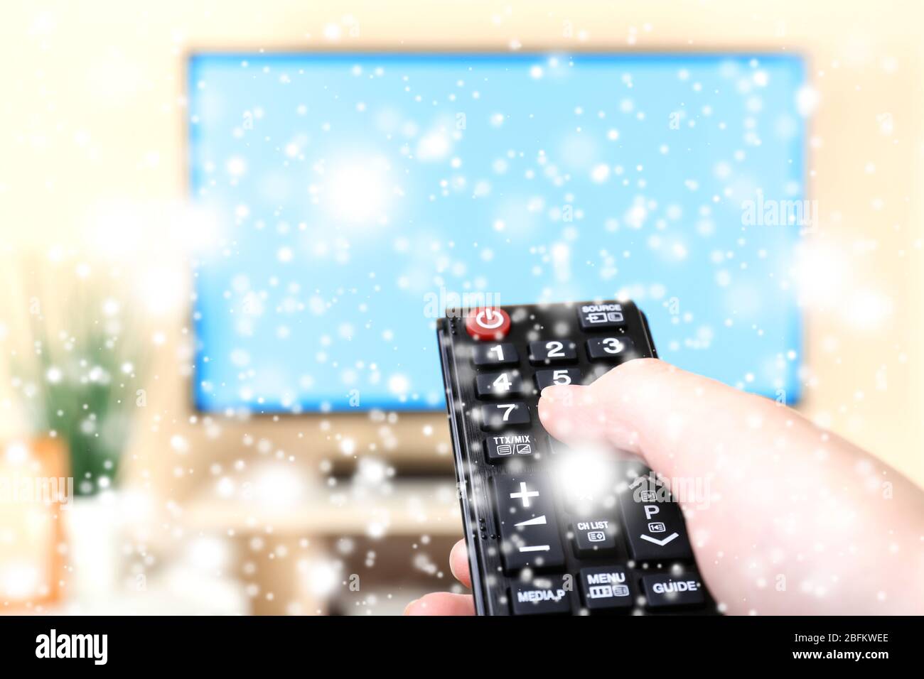Watching TV and using remote controller over snow effect Stock Photo ...