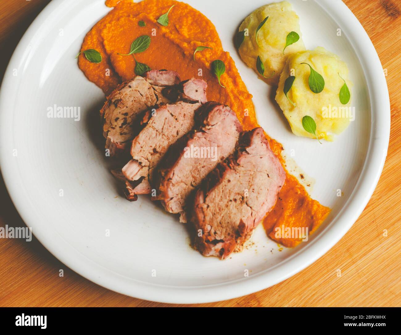 Pork fillet in a plate with carrot cream and fresh fruit Stock Photo ...