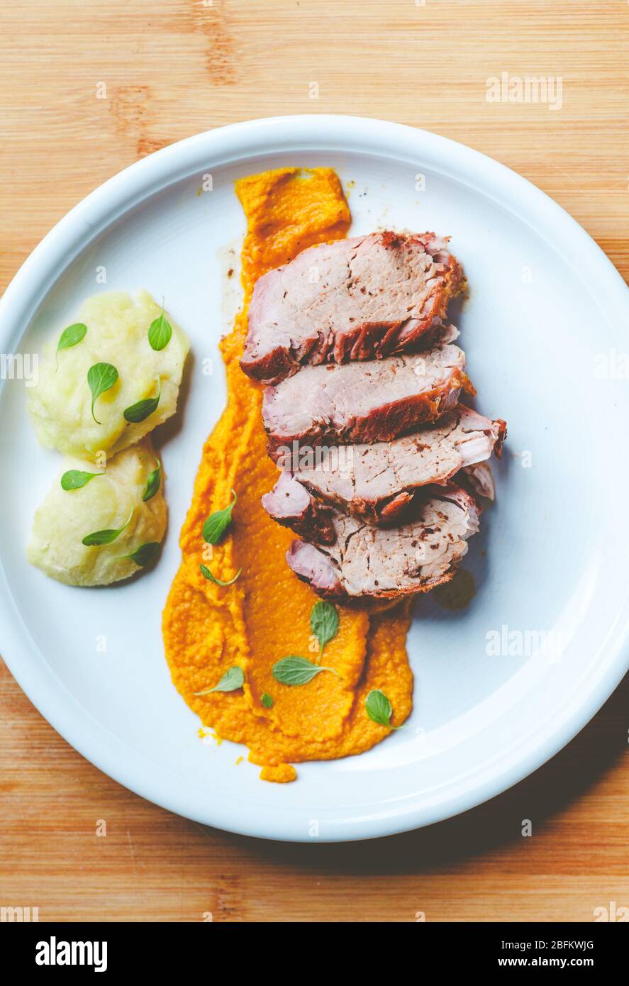 Pork fillet in a plate with carrot cream and fresh fruit Stock Photo ...