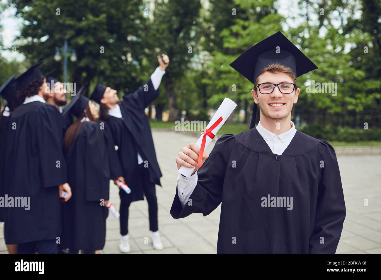 Man graduate is smiling against the background of university graduates ...