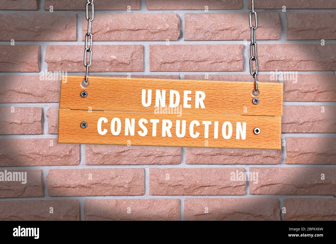 Wooden signboard with text Under Construction on brick wall background ...