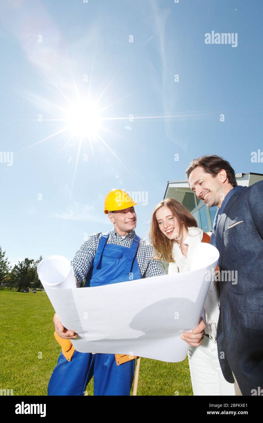 Foreman showing house design construction plan to a happy young couple ...