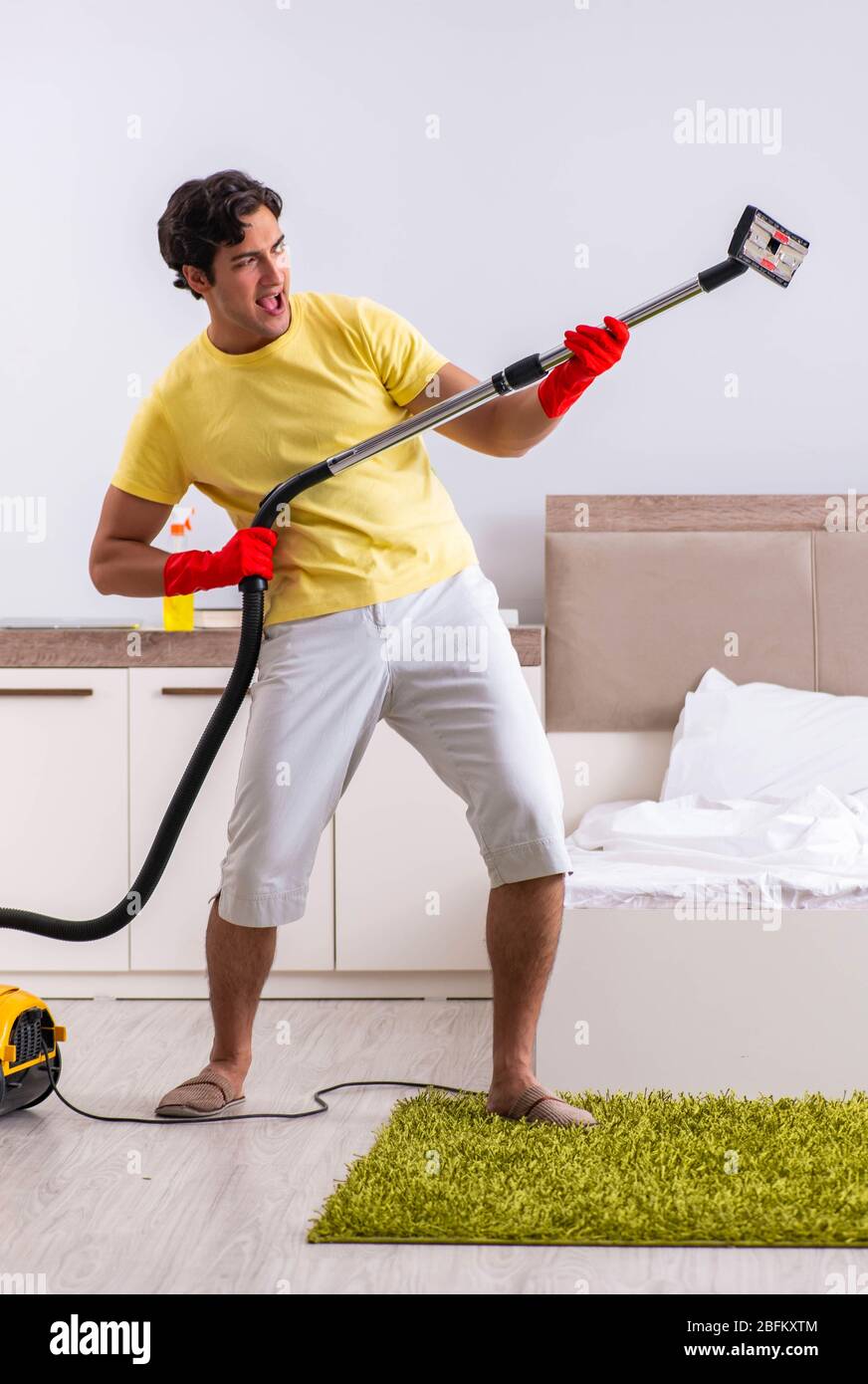 The young handsome man cleaning in the bedroom Stock Photo - Alamy
