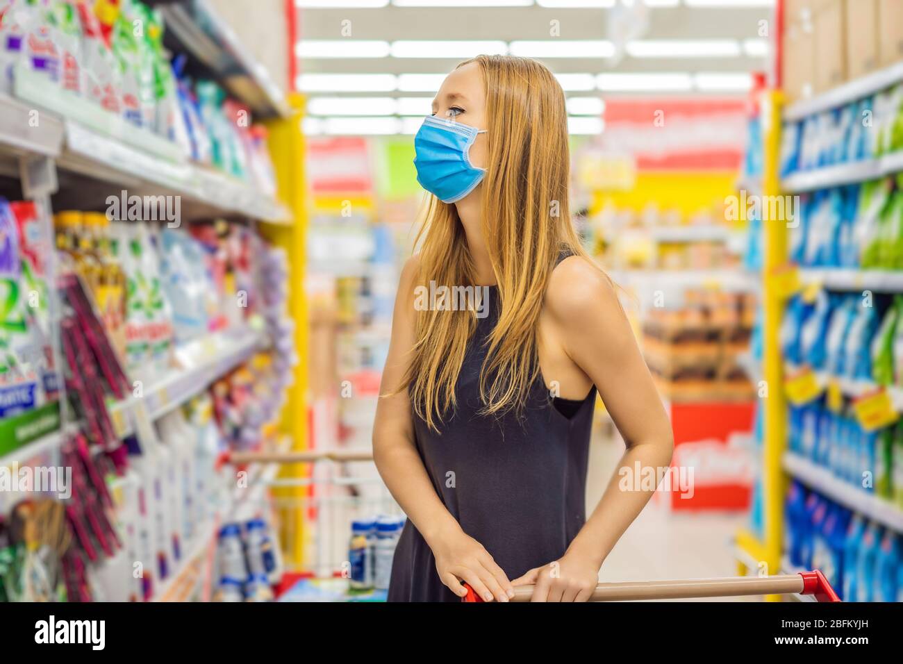 Alarmed female wears medical mask against coronavirus while grocery ...