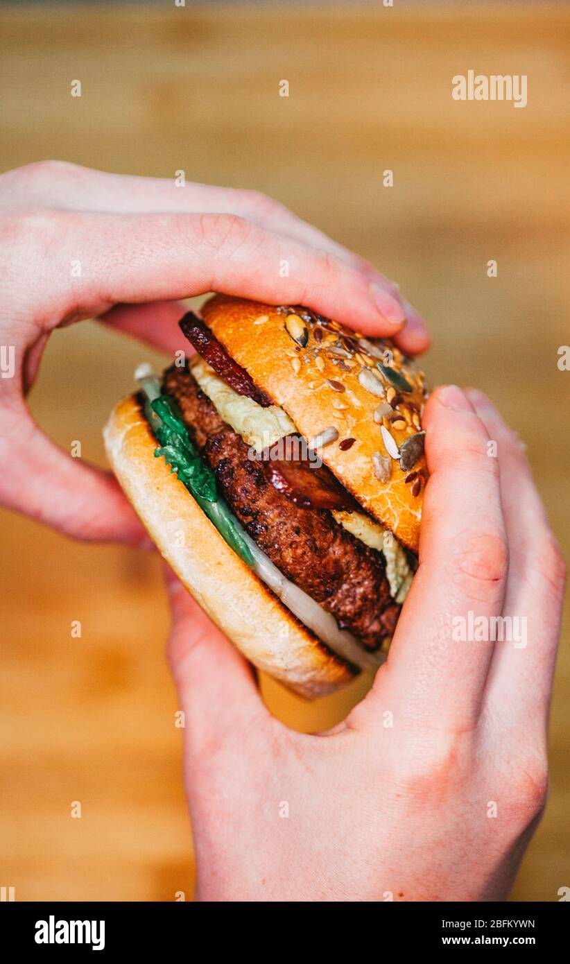 Gourmet Bacon Cheese burger with fresh salad and raw meat. Hands ...