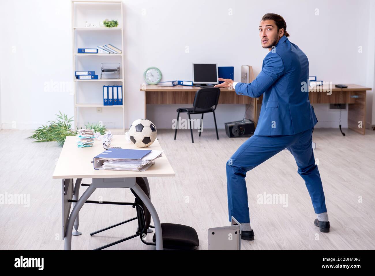 Young employee playing football in the office Stock Photo - Alamy