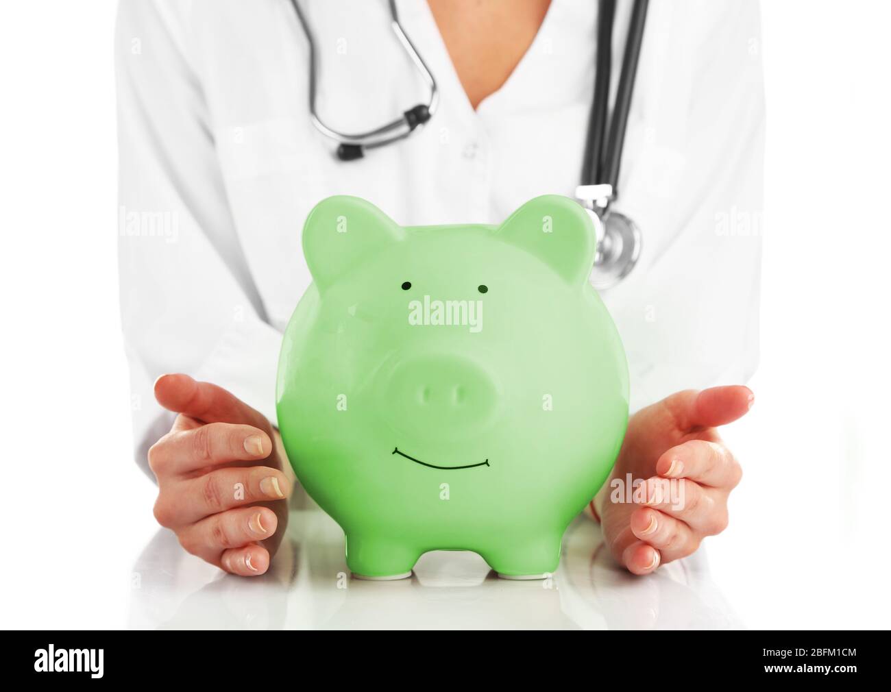 Doctor in white uniform with stethoscope holding green piggy bank ...