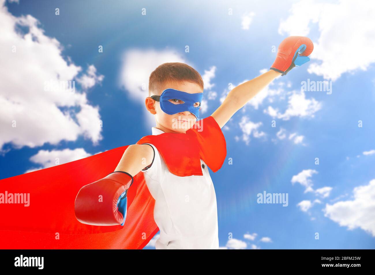 Boy dressed as superhero with boxing gloves on sky background Stock ...