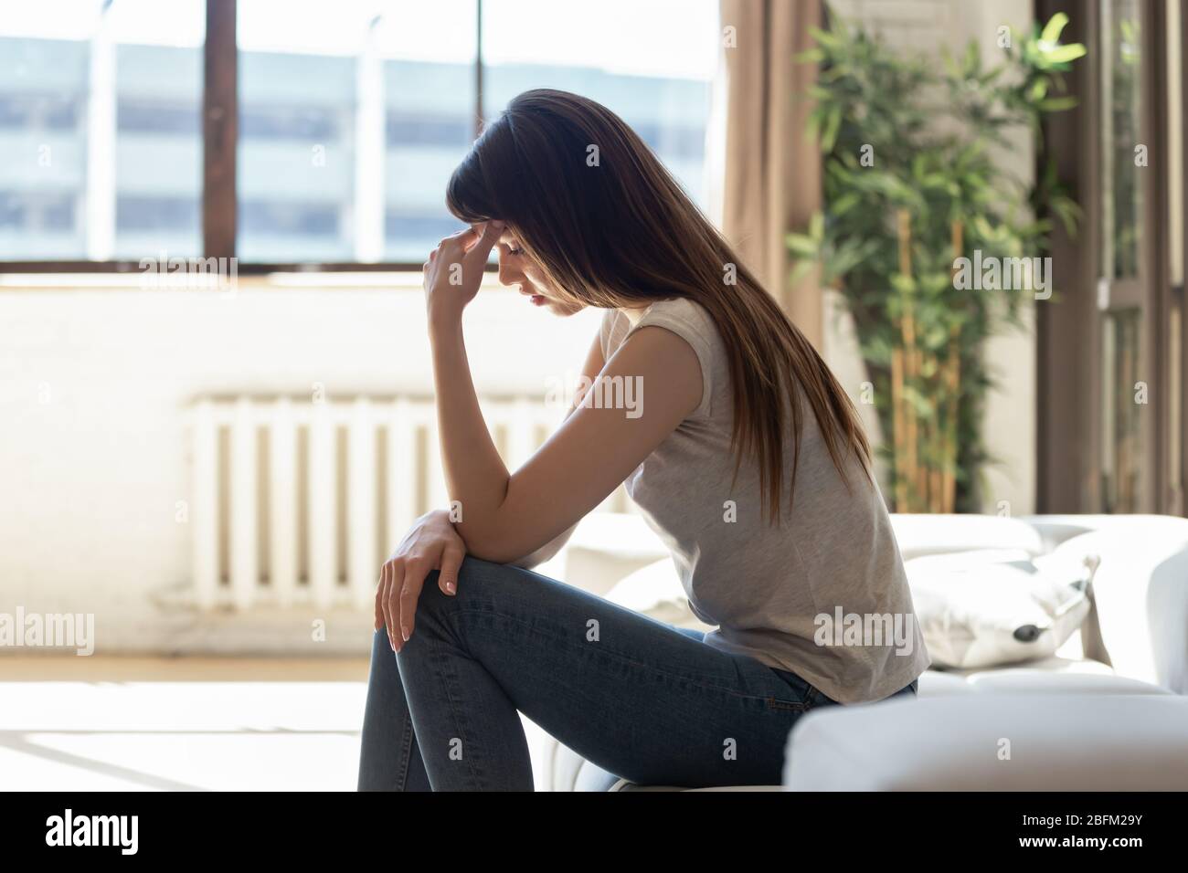 Unhappy young attractive woman holding forehead side view, suffering ...