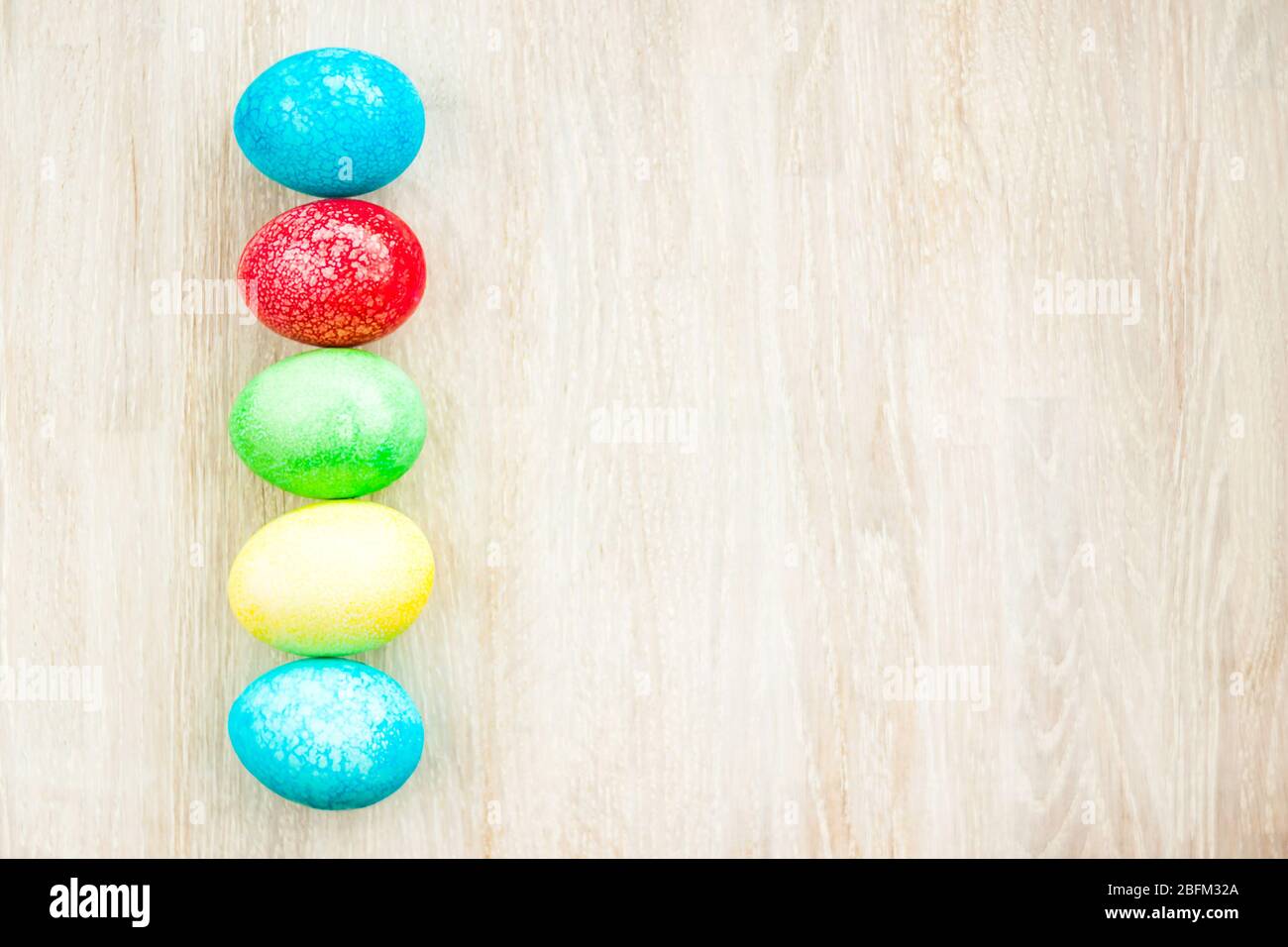 Colorful Easter egg side border on white wooden background flat lay ...
