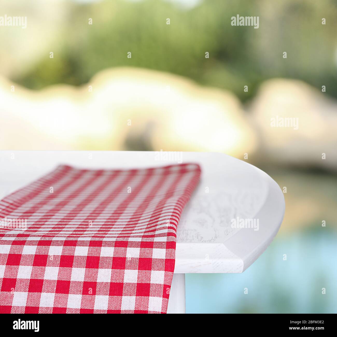 Wooden table with napkin on blurred nature background Stock Photo - Alamy