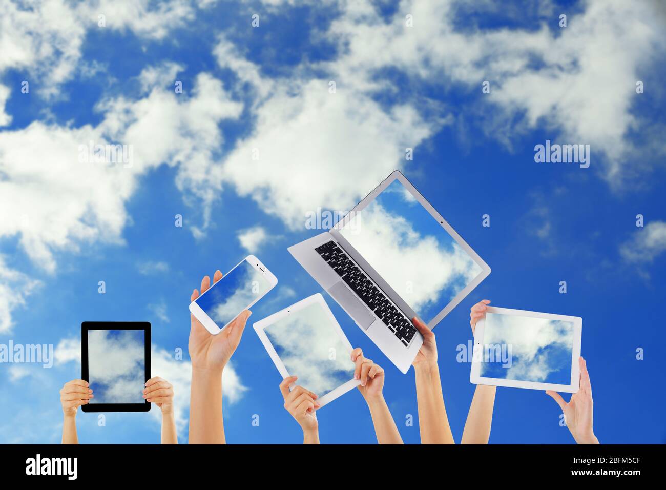 Hands holding electronic gadgets with sky on screens. Cloud computing concept Stock Photo - Alamy