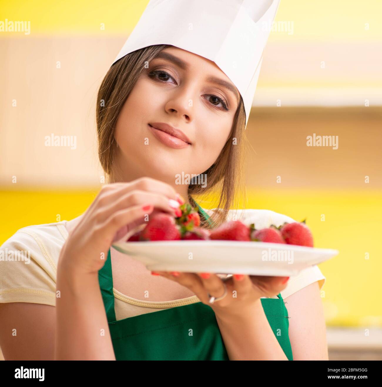 The young female cook eating strawberries Stock Photo - Alamy