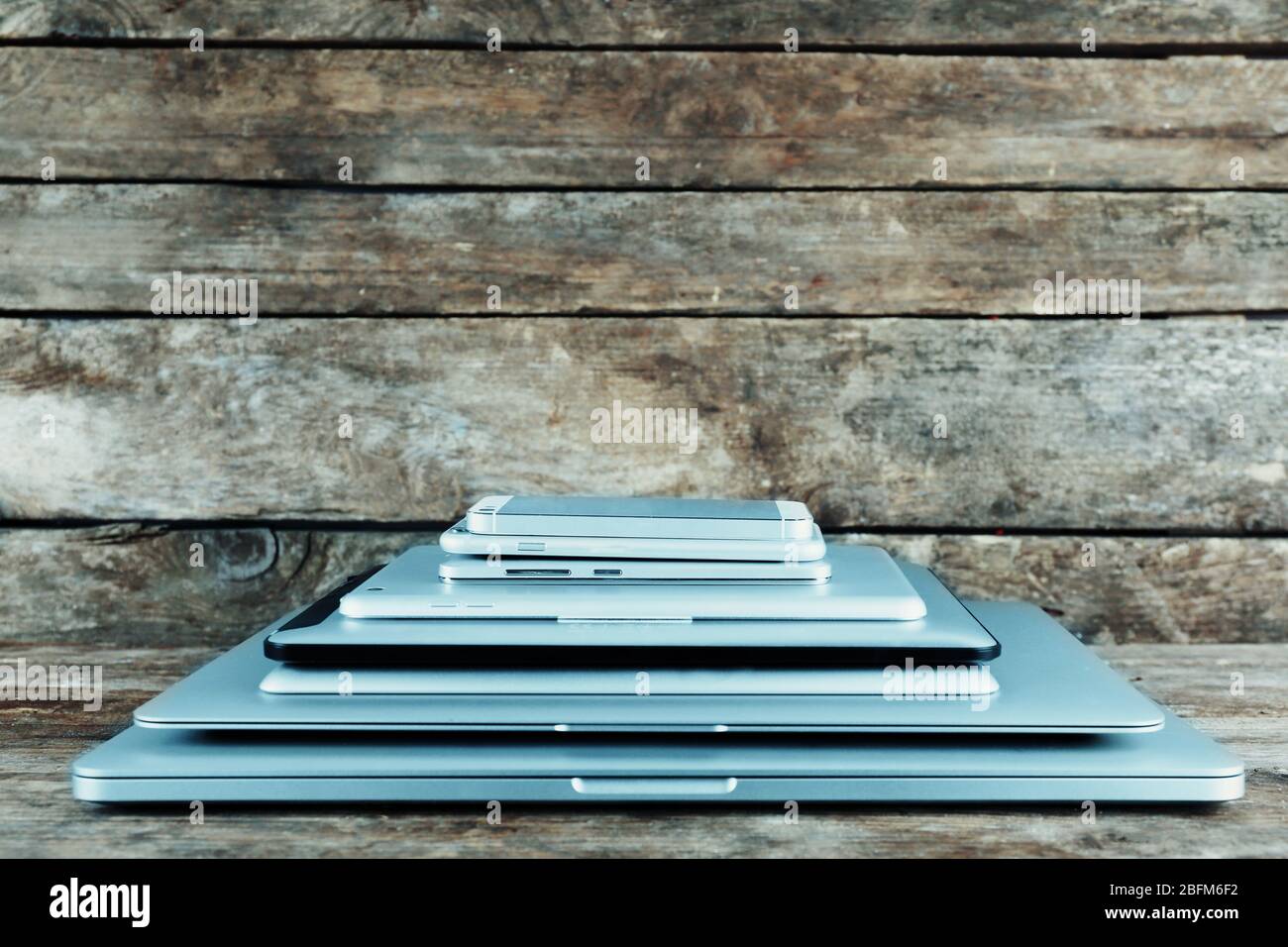 Pile of different modern electronics gadgets on old wooden background ...
